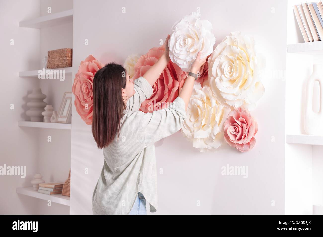 Woman decorating wall with beautiful paper flowers at home Stock Photo ...
