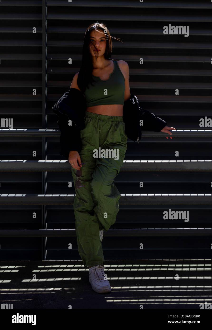 Beautiful young Gen Z woman relaxing in an urban scenery and looking at ...