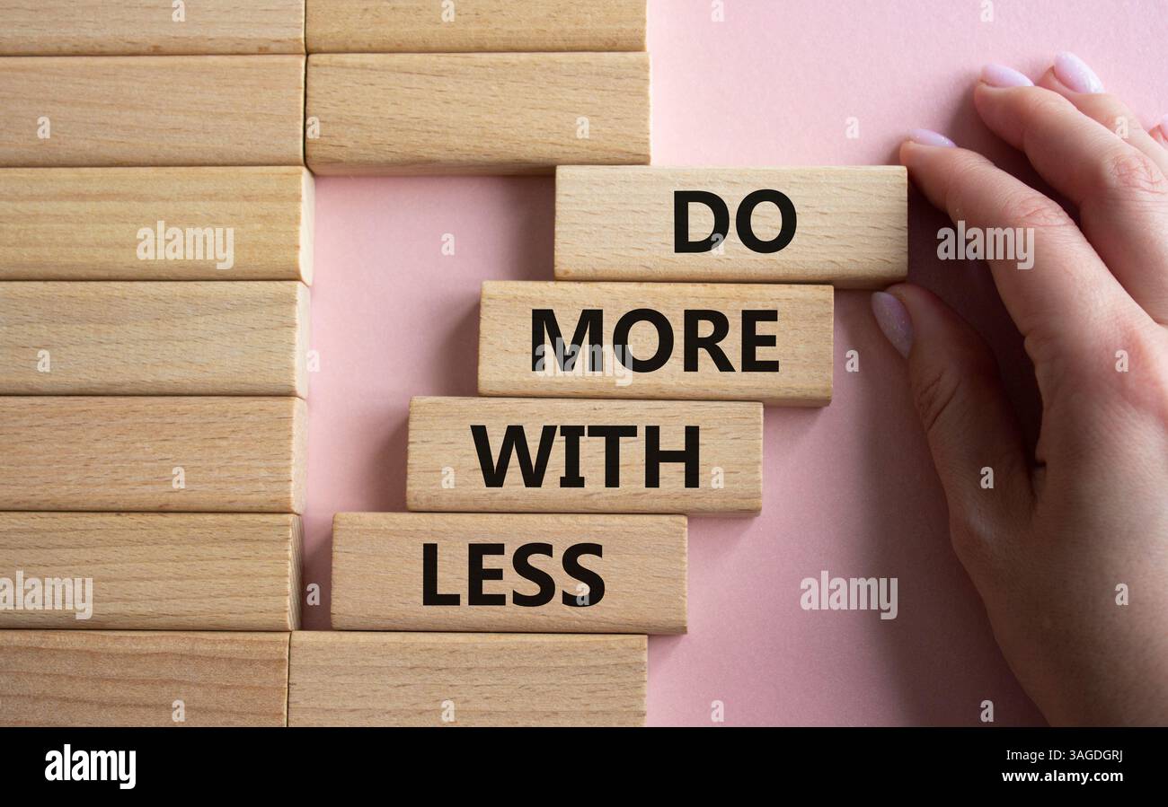 Do more with less symbol. Concept words Do more with less on wooden blocks. Beautiful pink ...