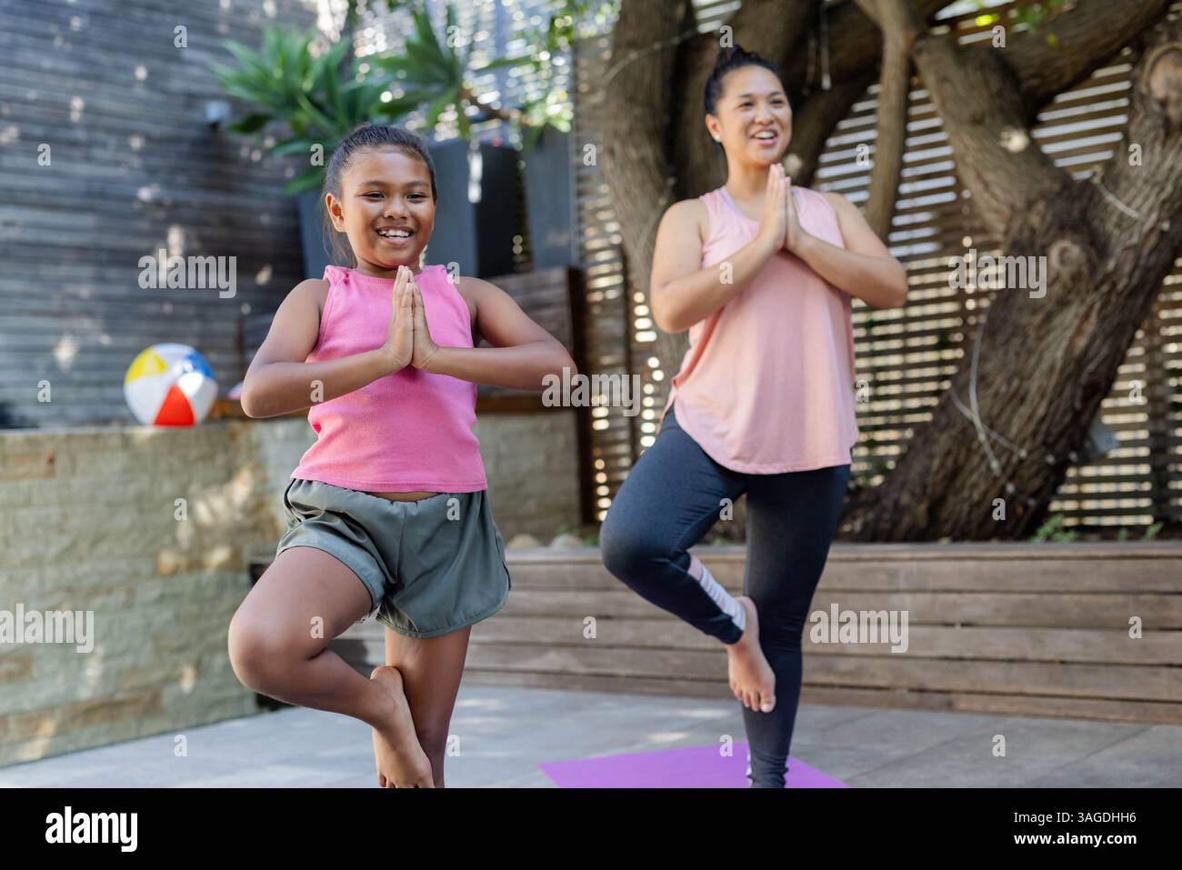 Mother and daughter practicing yoga together outdoors, enjoying quality ...