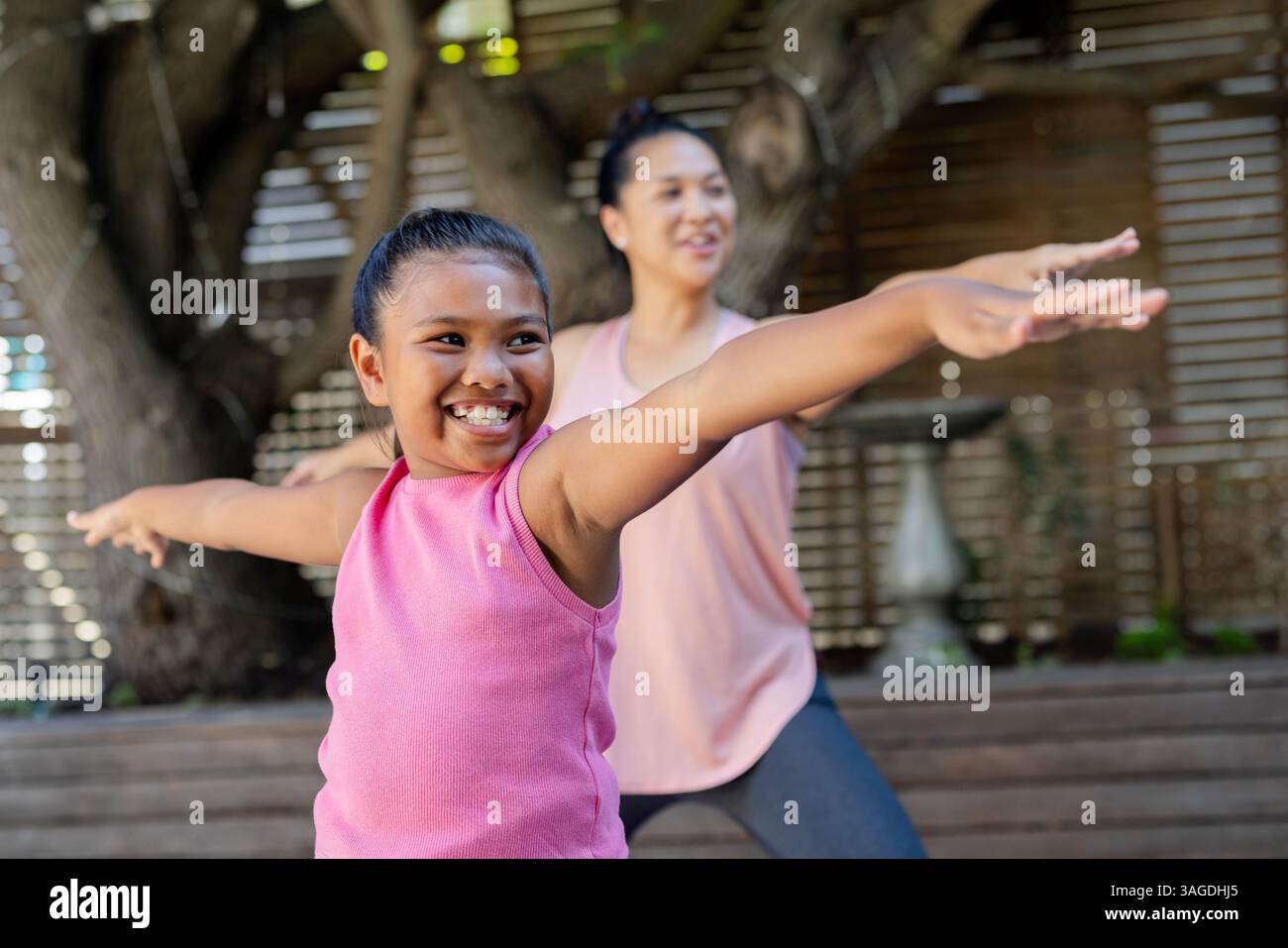 Mother and daughter practicing yoga outdoors, smiling and enjoying ...