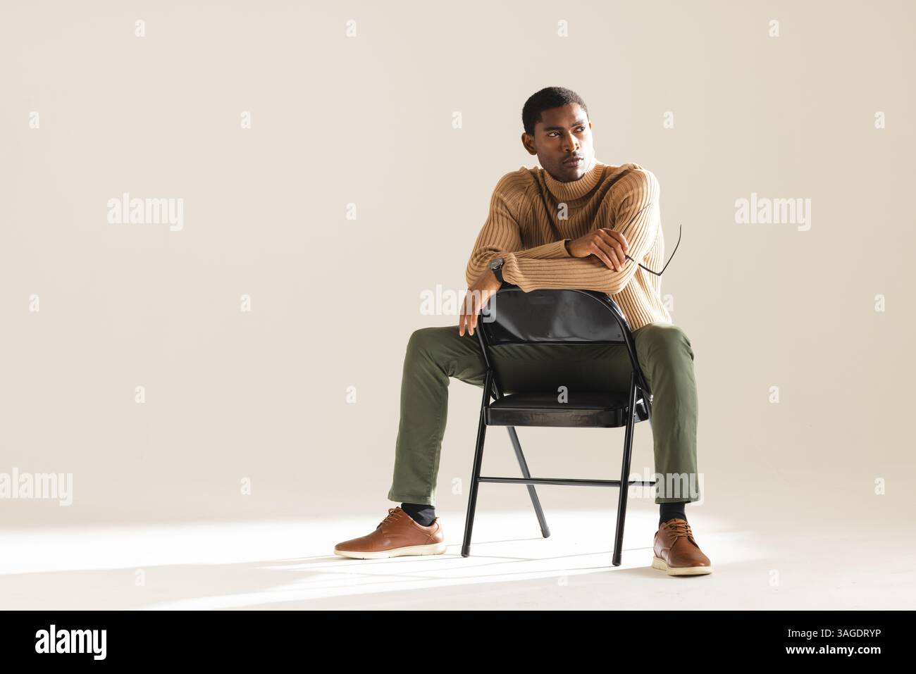 Confident man in stylish outfit sitting on chair in modern fashion ...