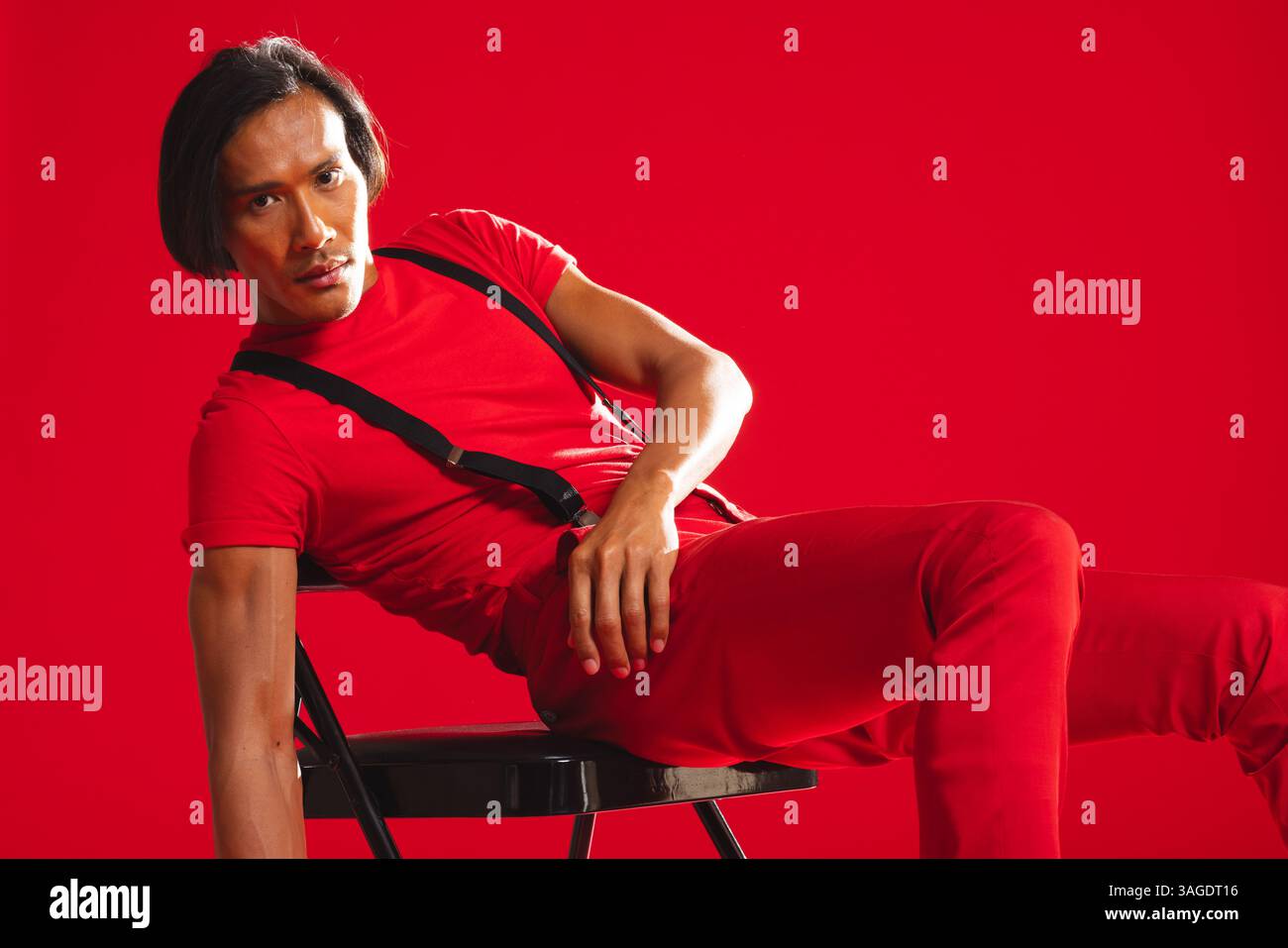 Man in red outfit posing confidently on chair in fashion studio ...