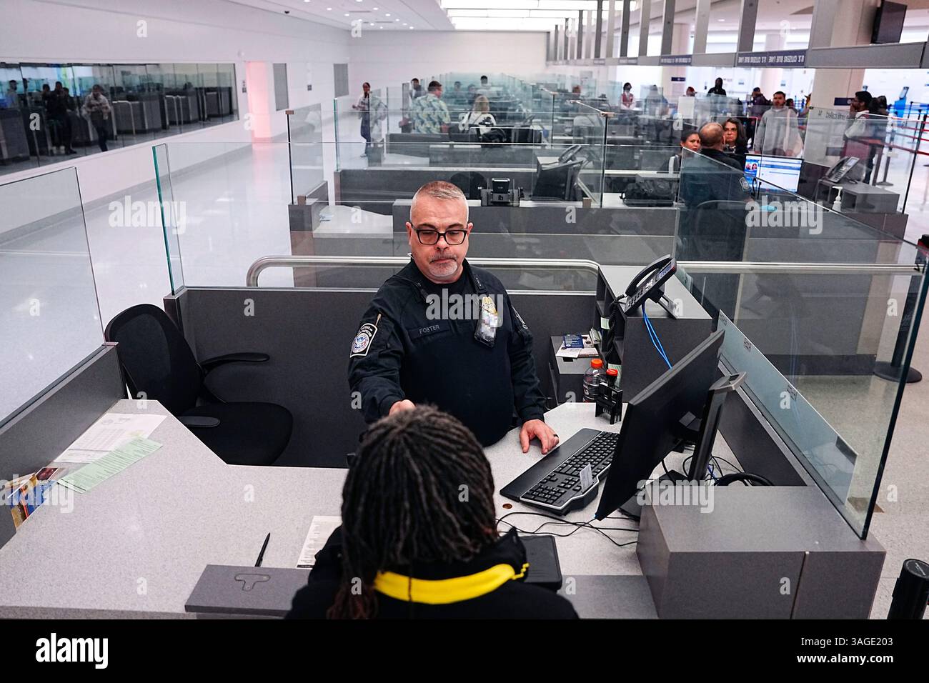 A U.S. Customs and Border Protection officer processes travelers ...