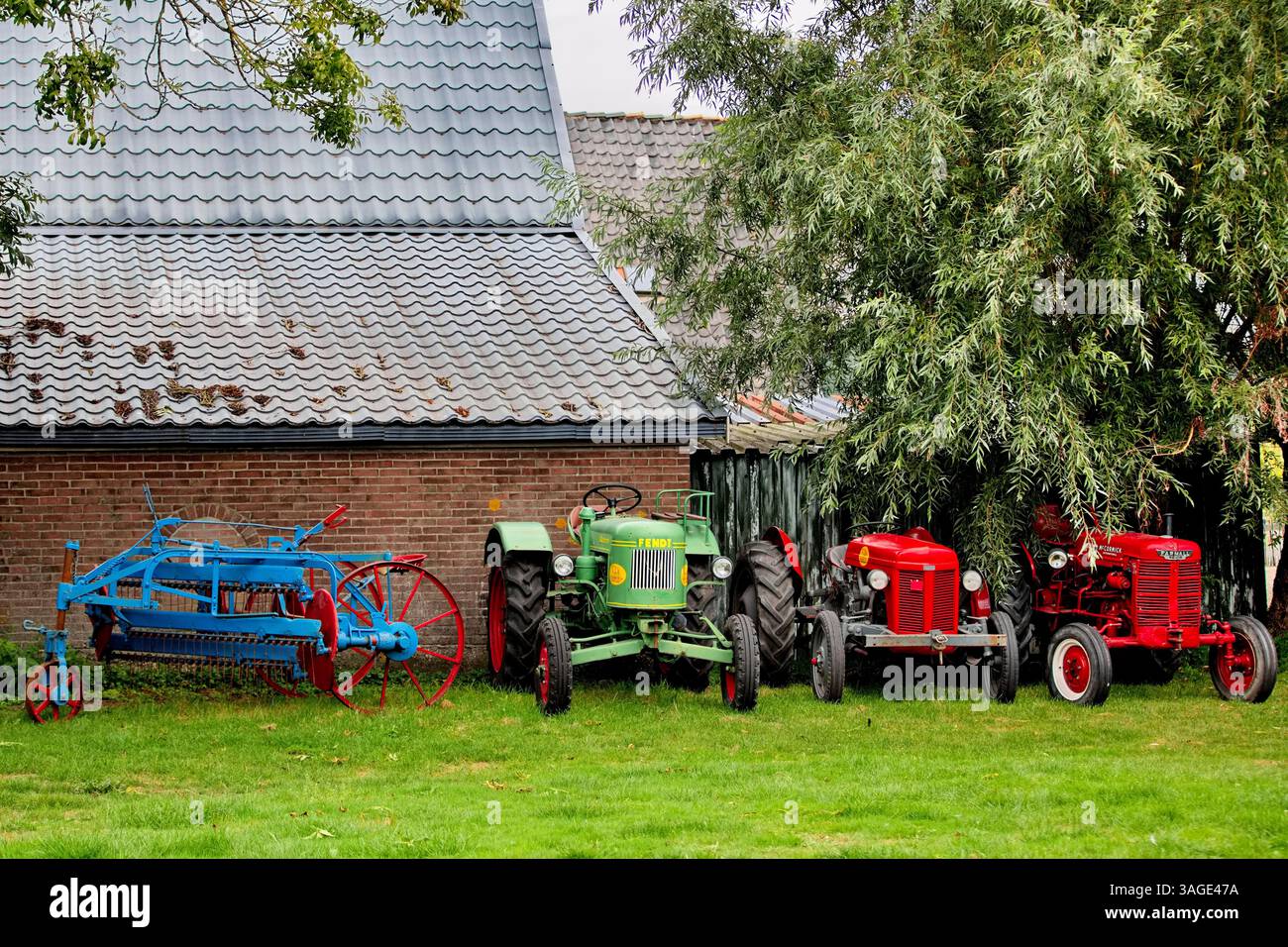Vintage tractors and farm equipment parked on grassy terrain next to a ...