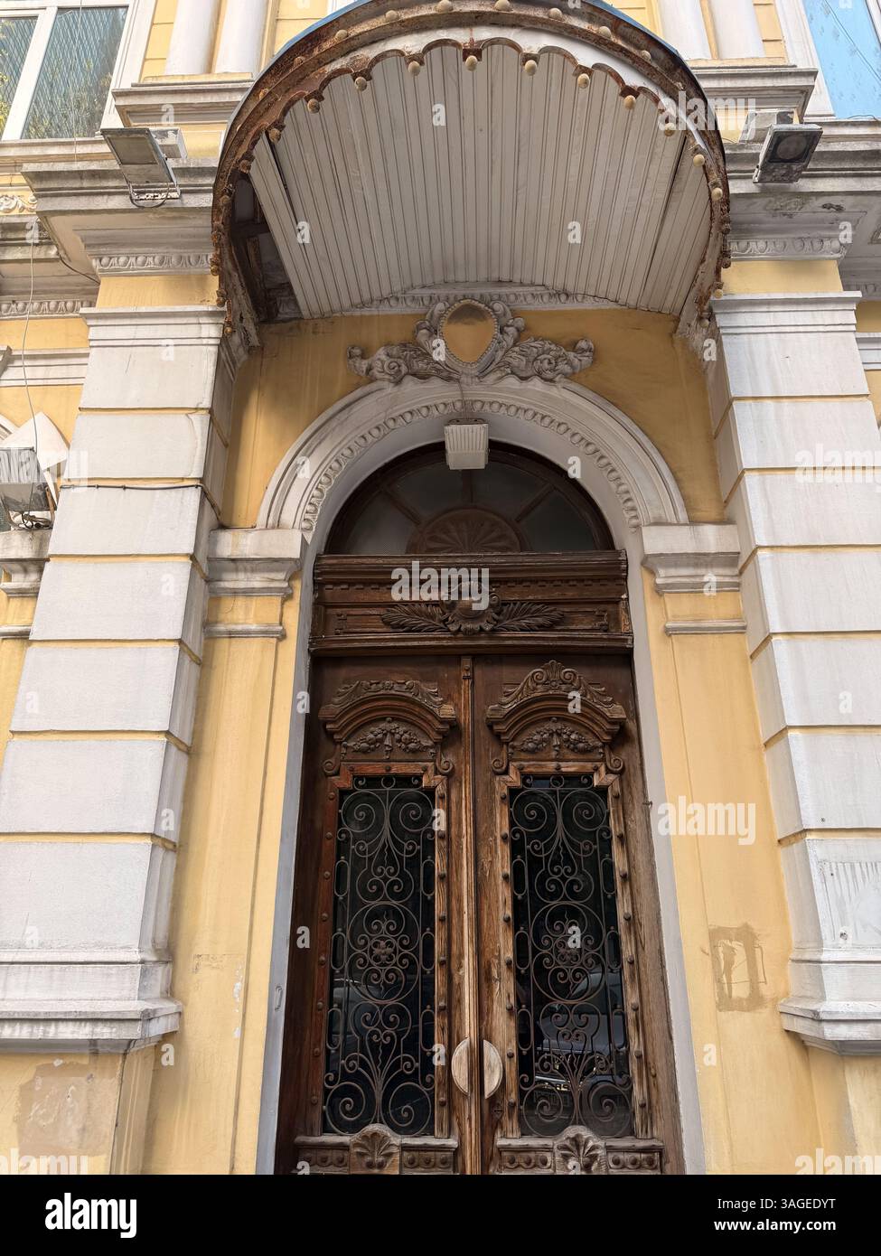 The photo shows the entrance of a yellow neoclassical building ...