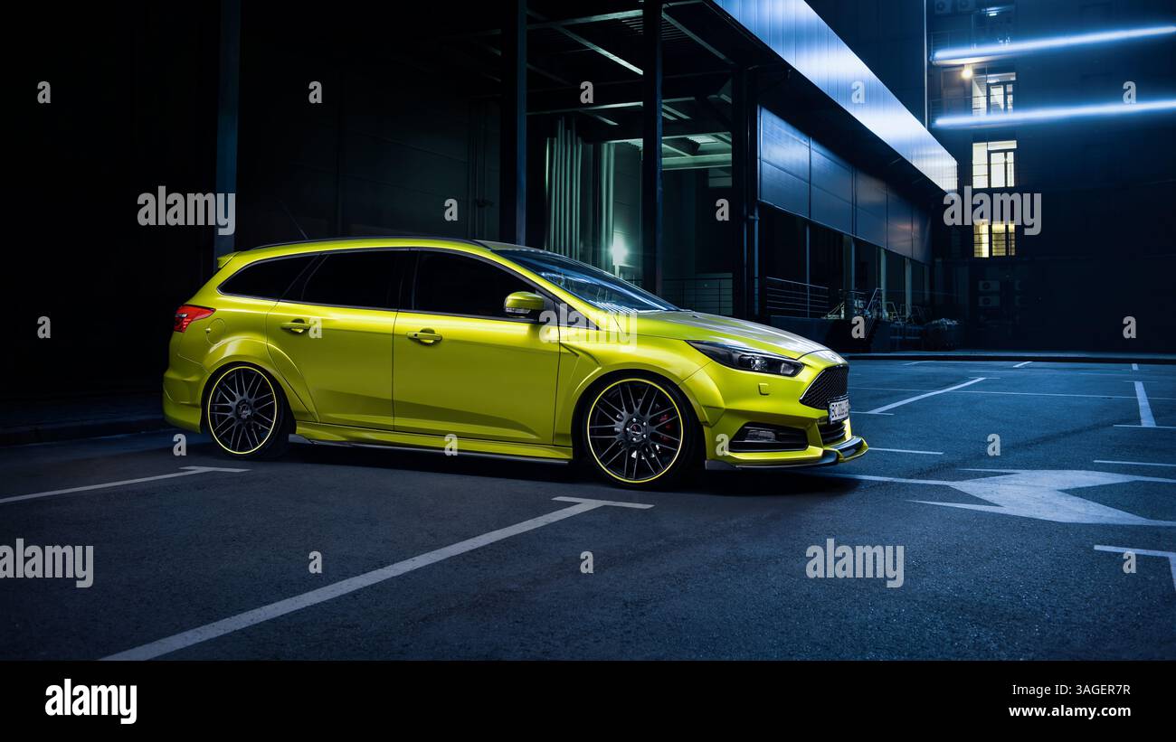 Lime green Ford Focus ST on dark city street. Front side view of sporty ...