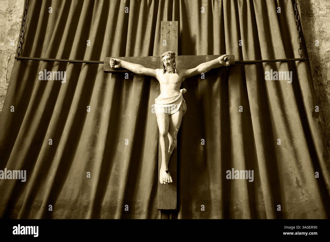 Old wooden crucifix of Jesus Christ isolated on drapery background in medieval church. Sepia ...