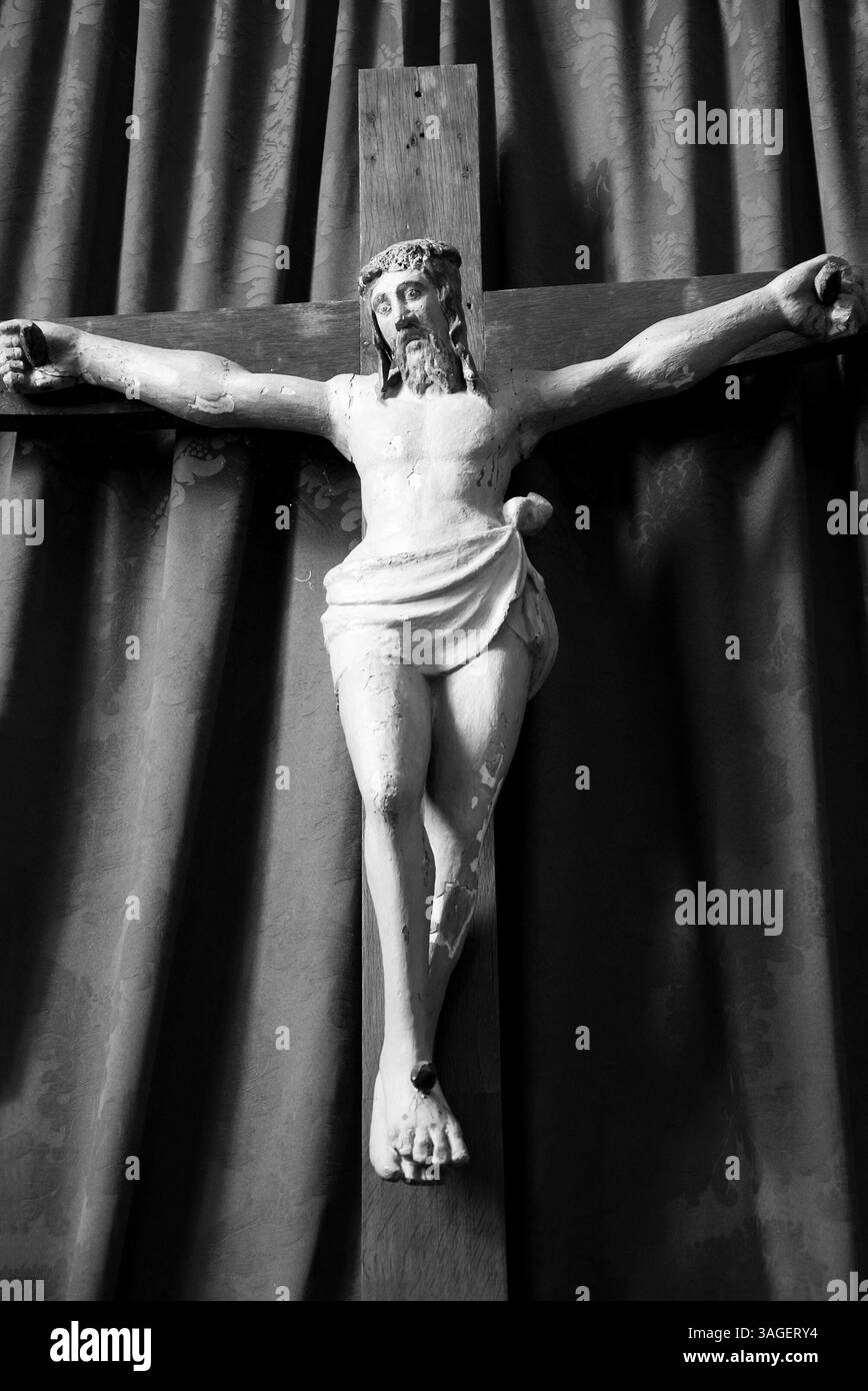 Old wooden crucifix of Jesus Christ isolated on drapery background in medieval church. Black ...