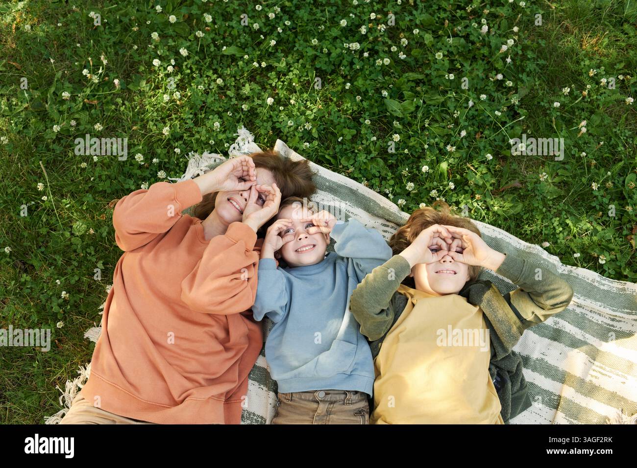 Mother and Two Boys on Blanket and Making Silly Faces Looking Up Stock ...