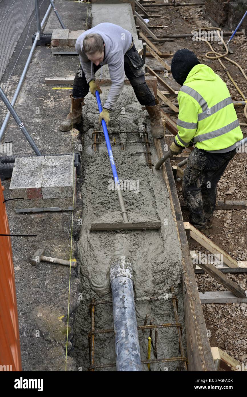 Builders levelling pumped concrete going into timber shuttered steel ...