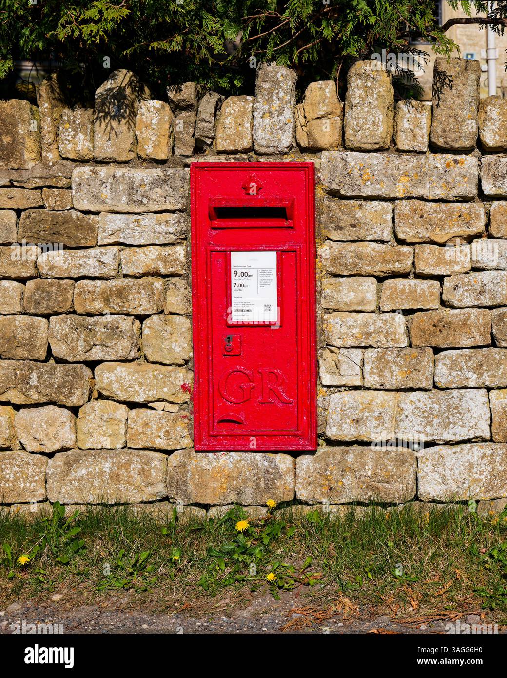 A red letter box mounted in a dry stone wall in the Cotswold village of ...