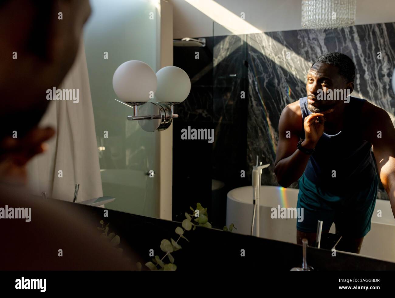 African American man grooming in modern bathroom, checking reflection ...