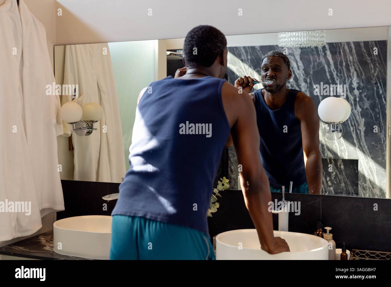 Man brushing teeth in modern bathroom, starting morning routine with ...