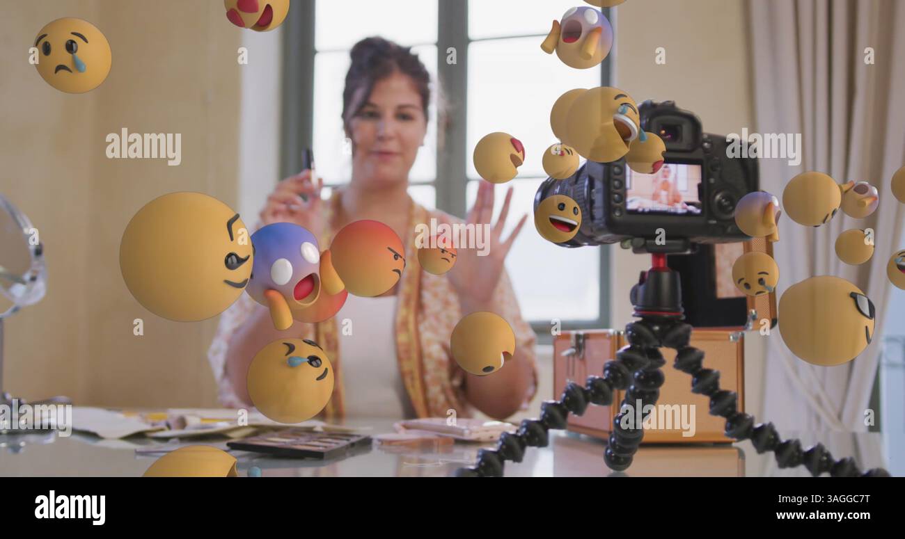 Image of emoji icons over female vlogger in camera viewer recording ...