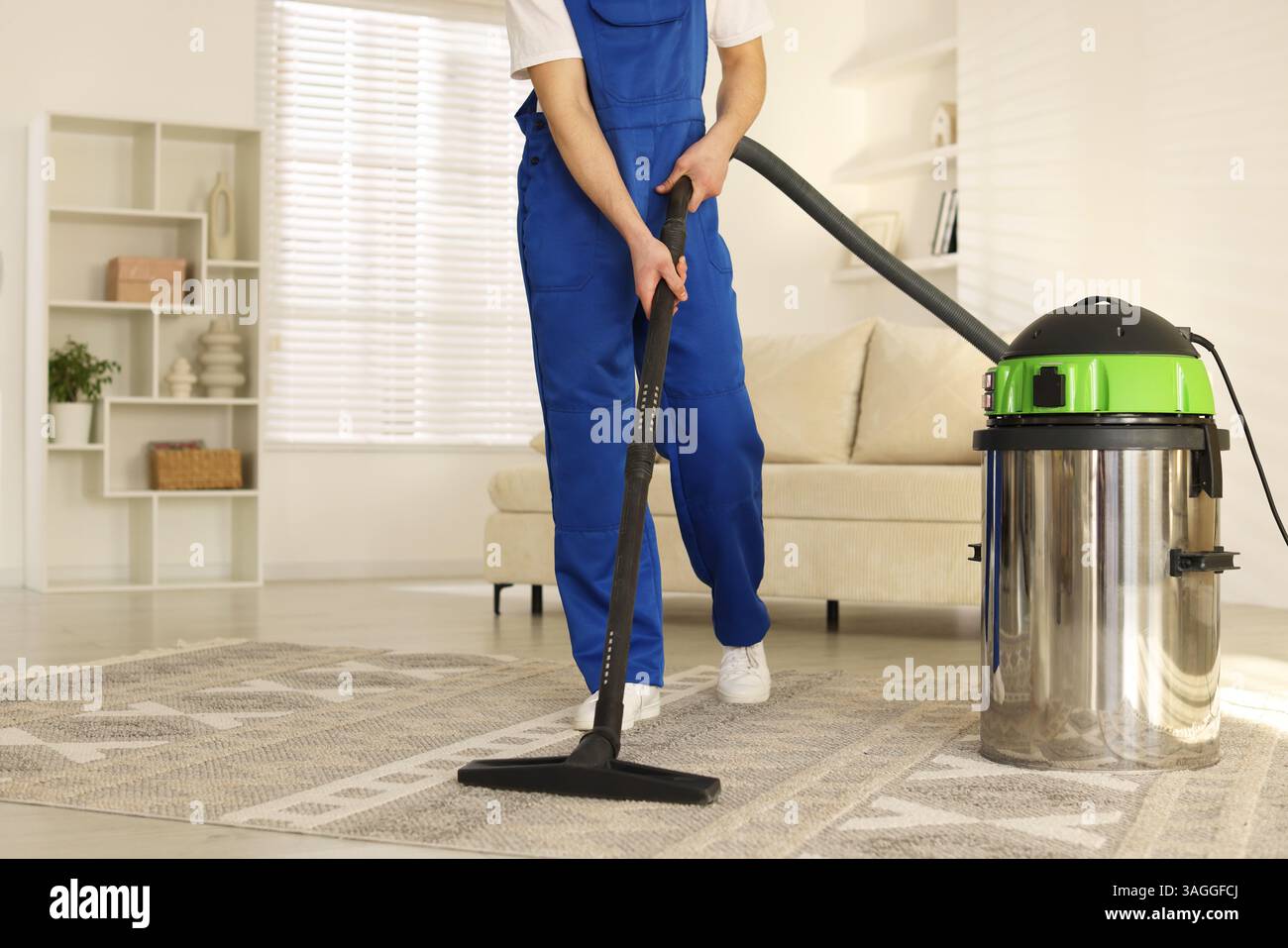 Cleaning service worker vacuuming rug with professional vacuum cleaner ...