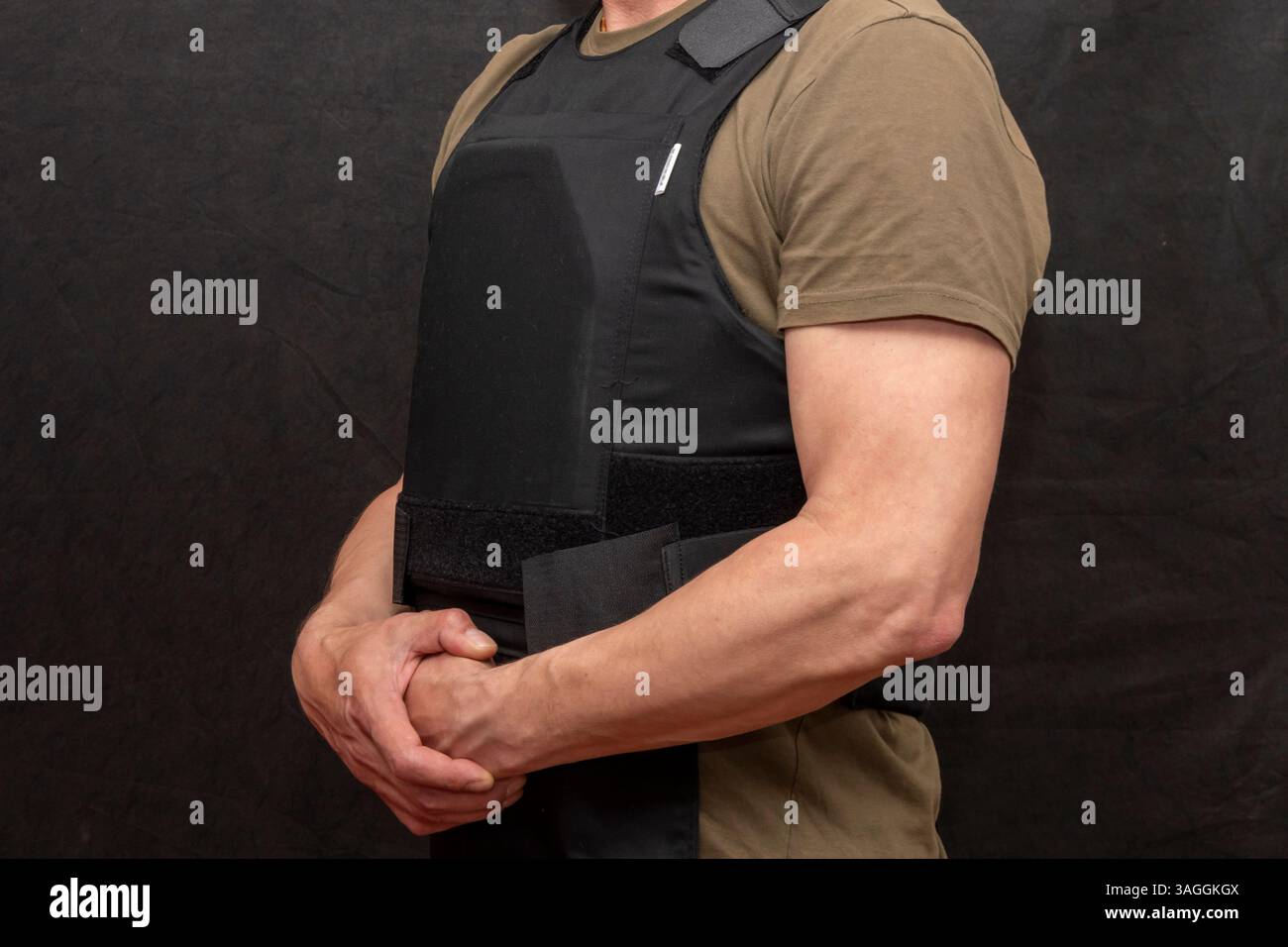 A muscular military man in a bulletproof vest on a black background ...