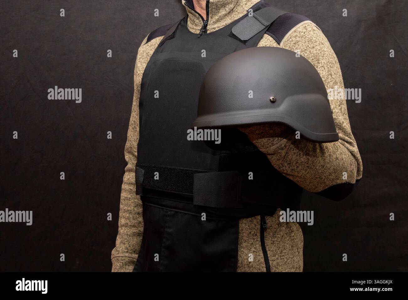 A military man in a bulletproof vest holds an army helmet in his hand ...