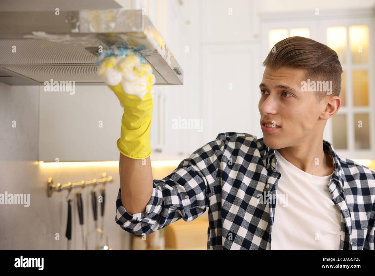 Man cleaning kitchen hood with sponge at home Stock Photo - Alamy