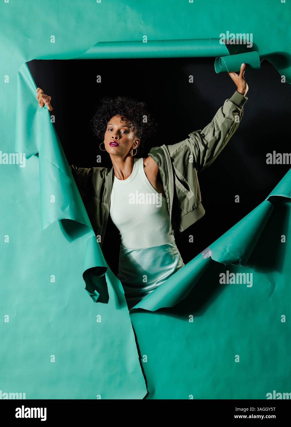 Breaking through paper backdrop, African American woman showing ...