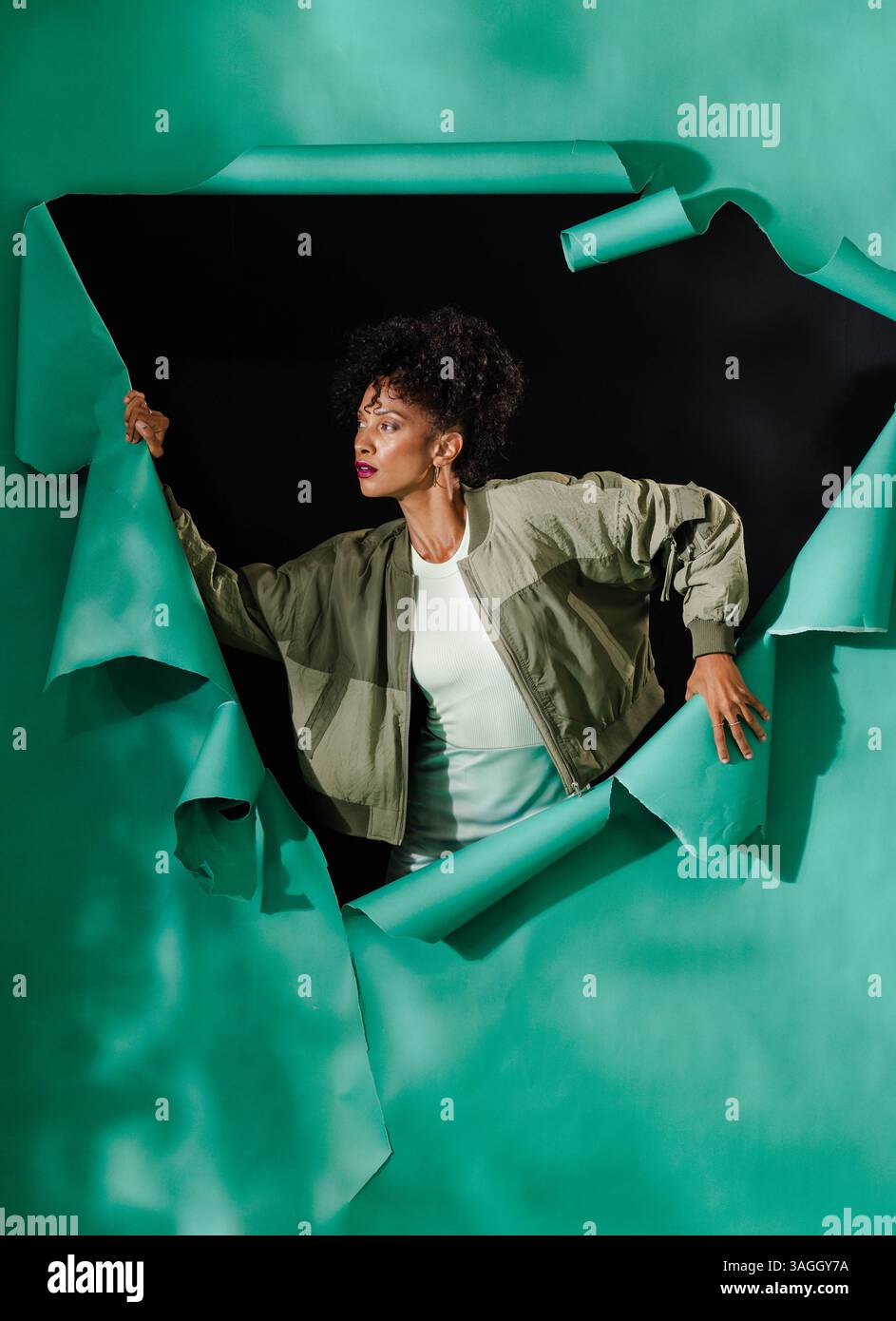 Woman breaking through green paper wall, expressing determination and ...
