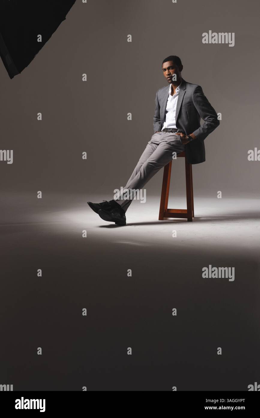 Confident man in stylish suit sitting on stool in fashion studio. style ...