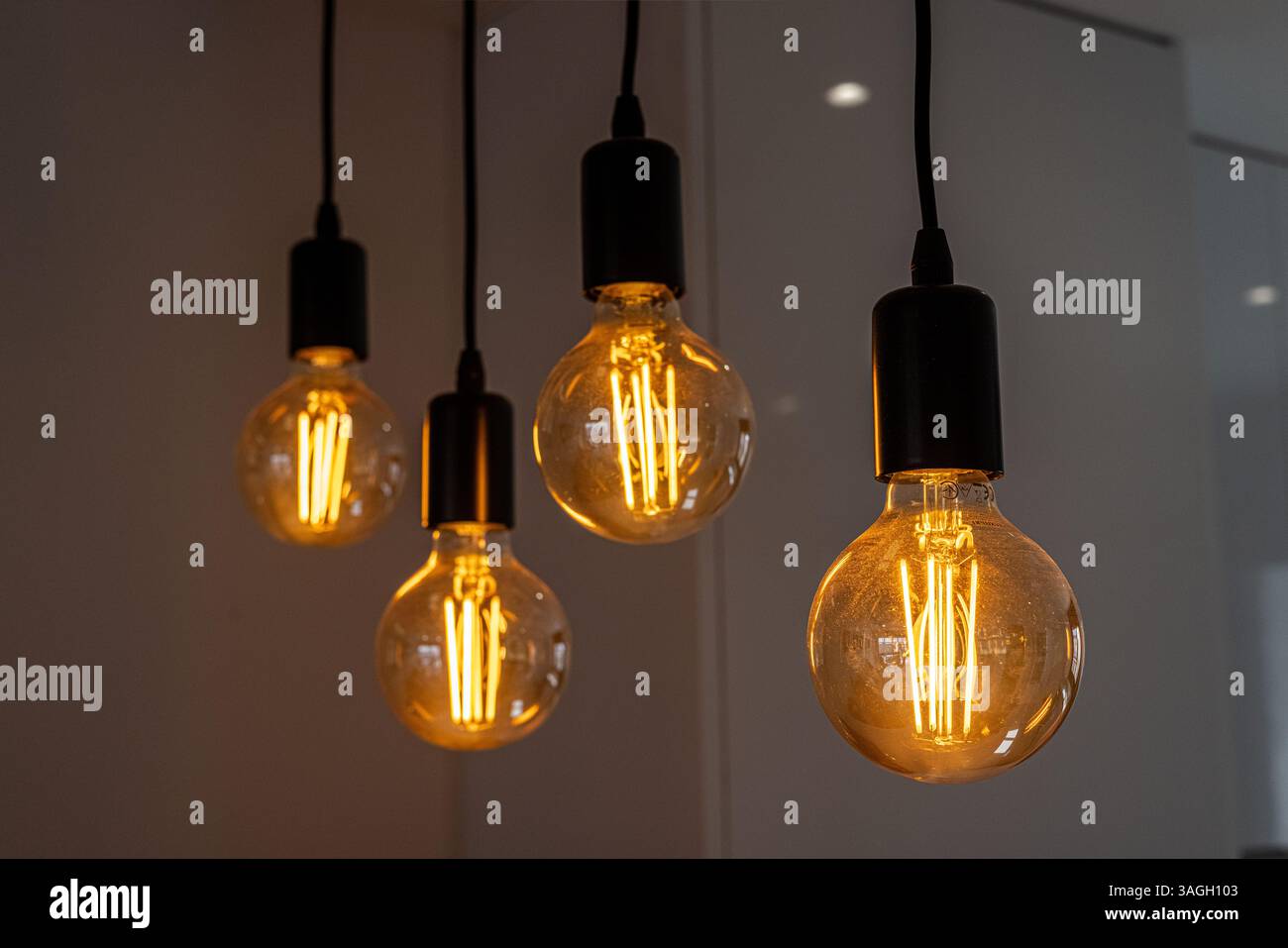 A stylish interior shot of four warm glowing Edison filament bulbs ...