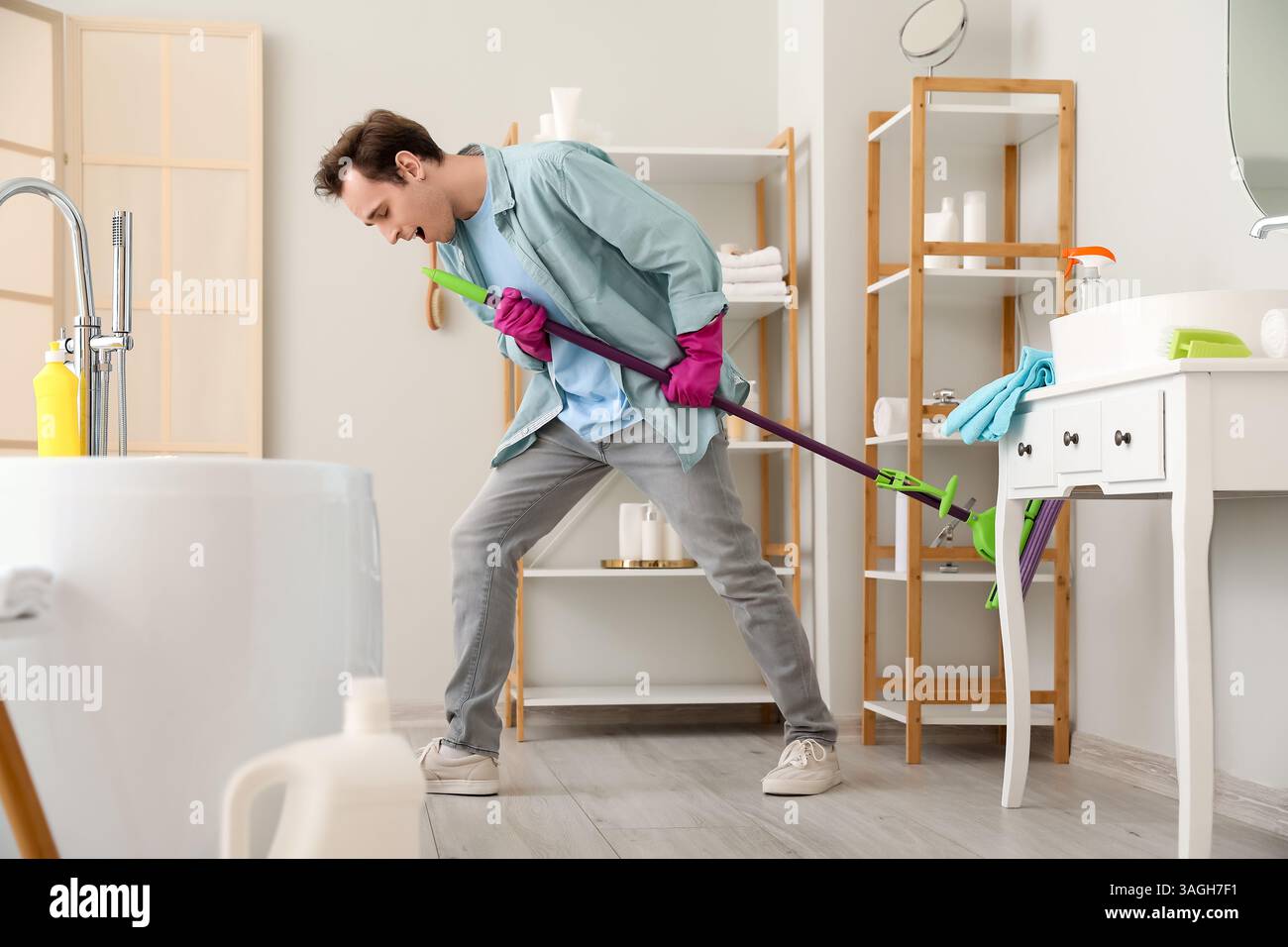 Young man having fun while mopping floor in bathroom Stock Photo - Alamy