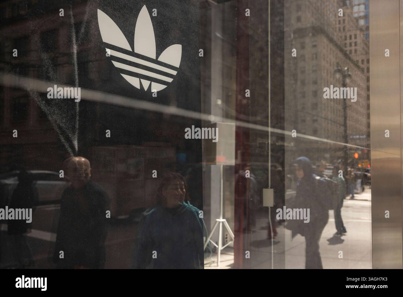 Pedestrians are reflected in an Adidas store window on 5th Avenue in New York, Tuesday, April 8 ...