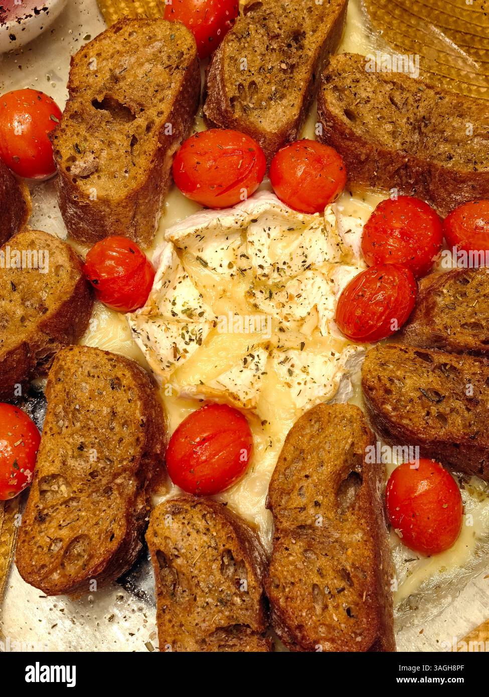 Golden brown slices of bread surround roasted cherry tomatoes, baked to ...