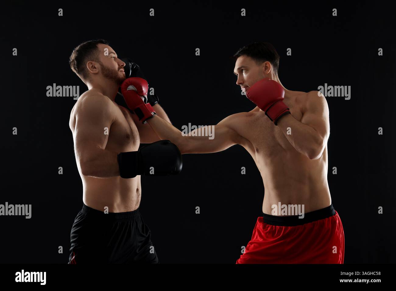 Men in boxing gloves fighting on black background Stock Photo - Alamy