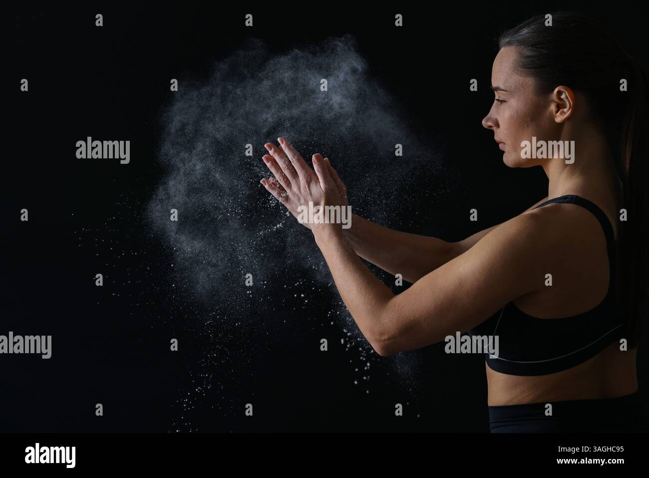 Woman clapping hands with talcum powder before training on black ...