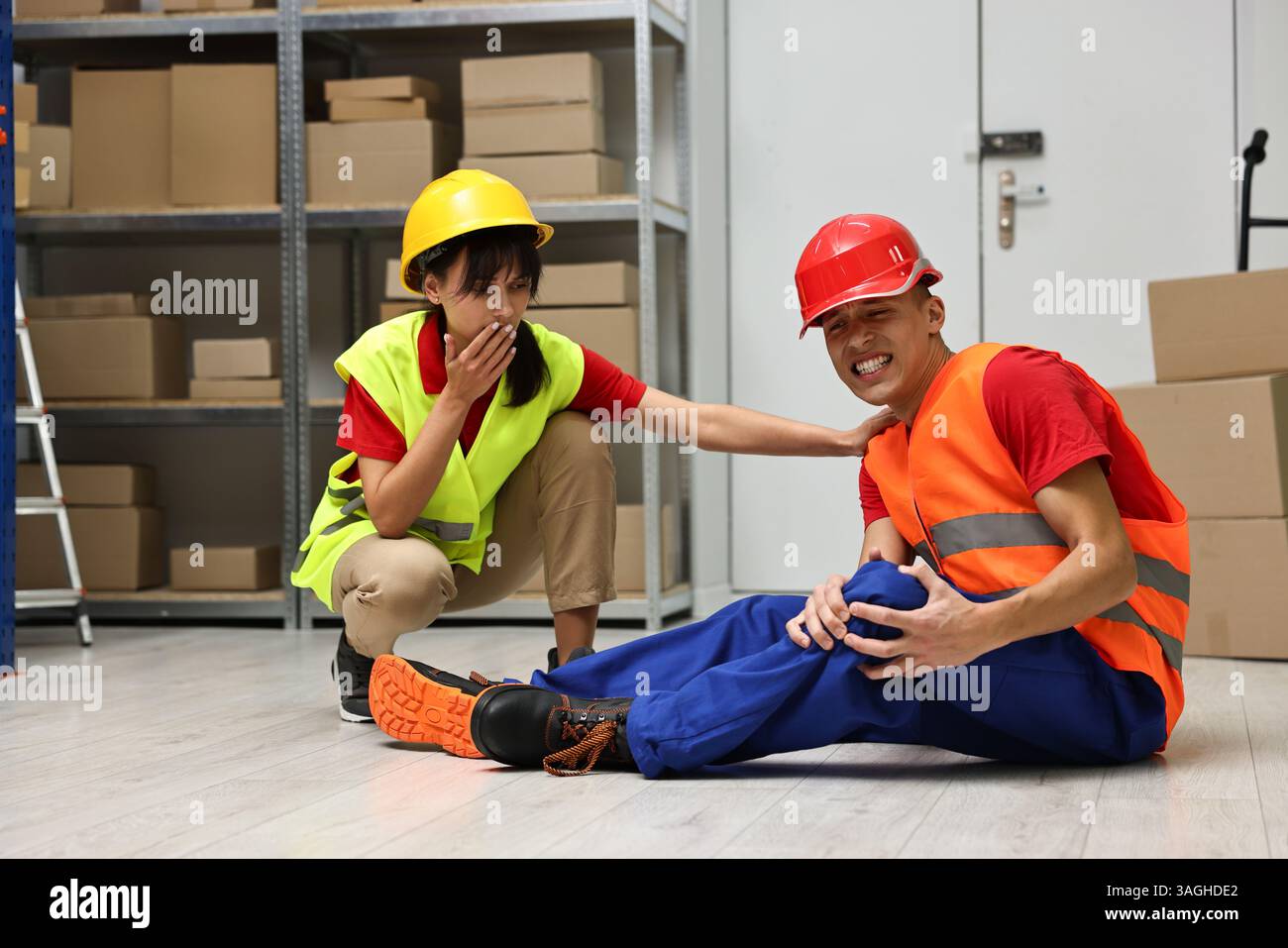 Accident at work. Woman helping her injured colleague in warehouse ...