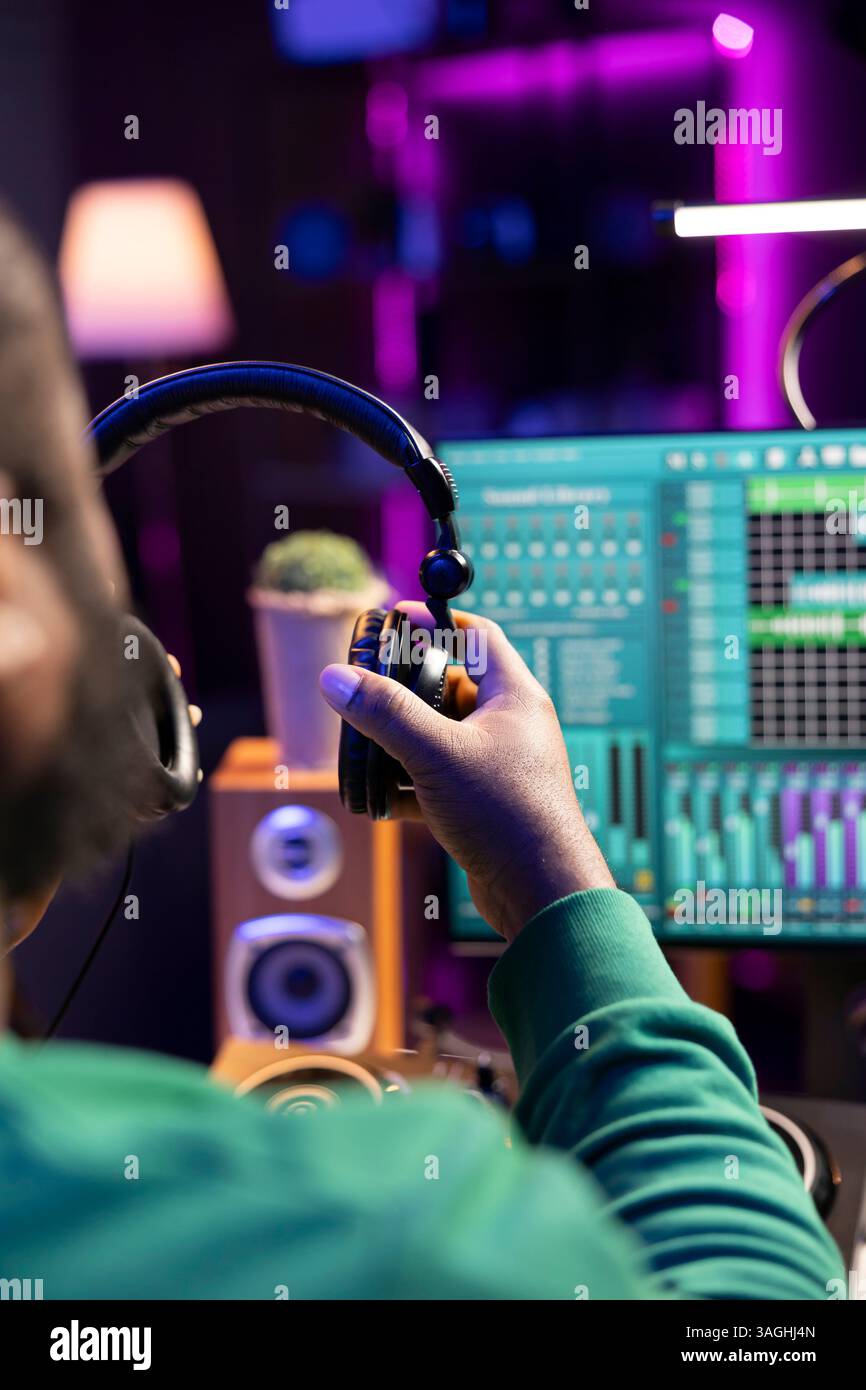 Music producer using his headphones for a mix and master session ...
