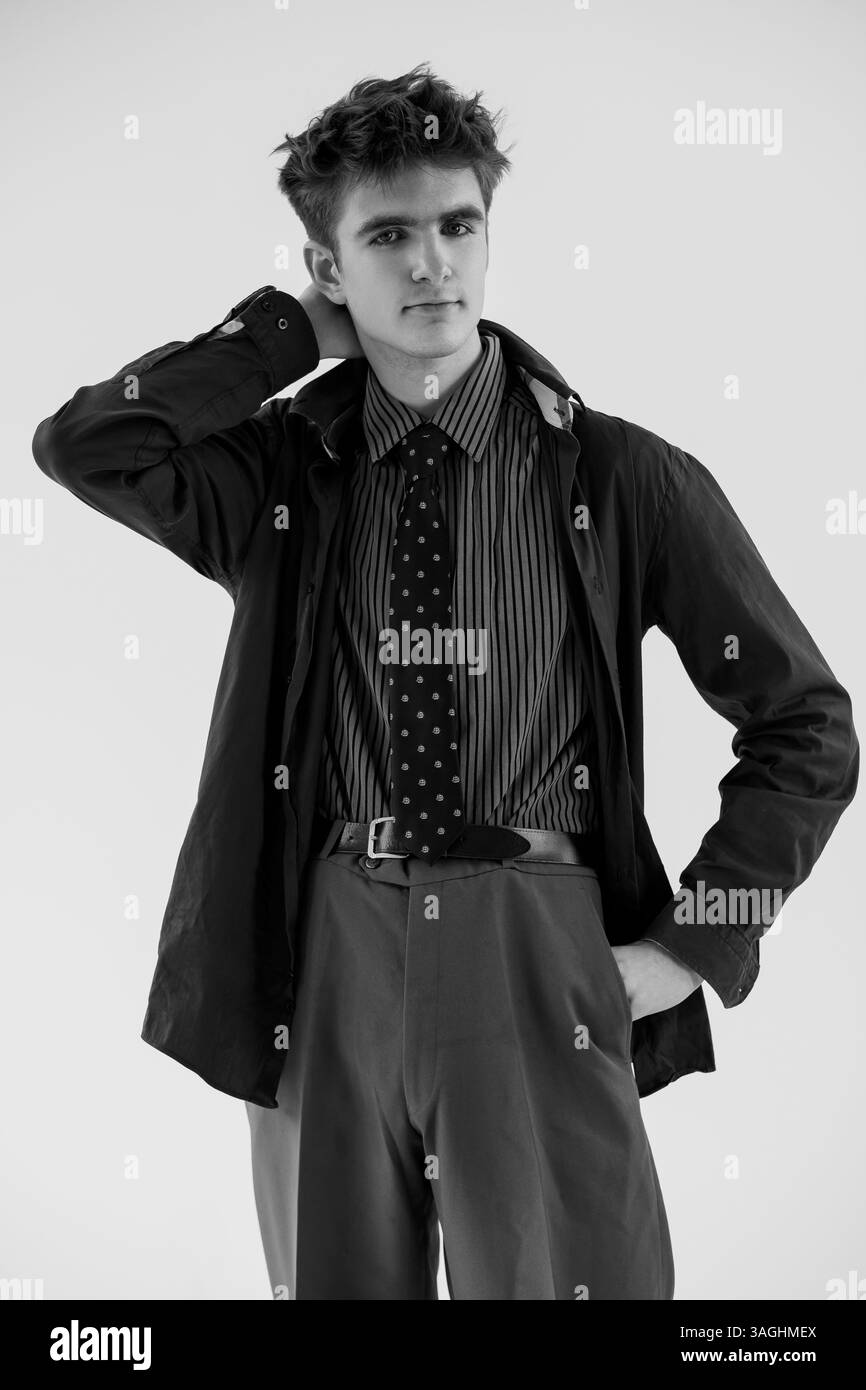 Stylish young man in formal attire posing with hand on neck against a ...