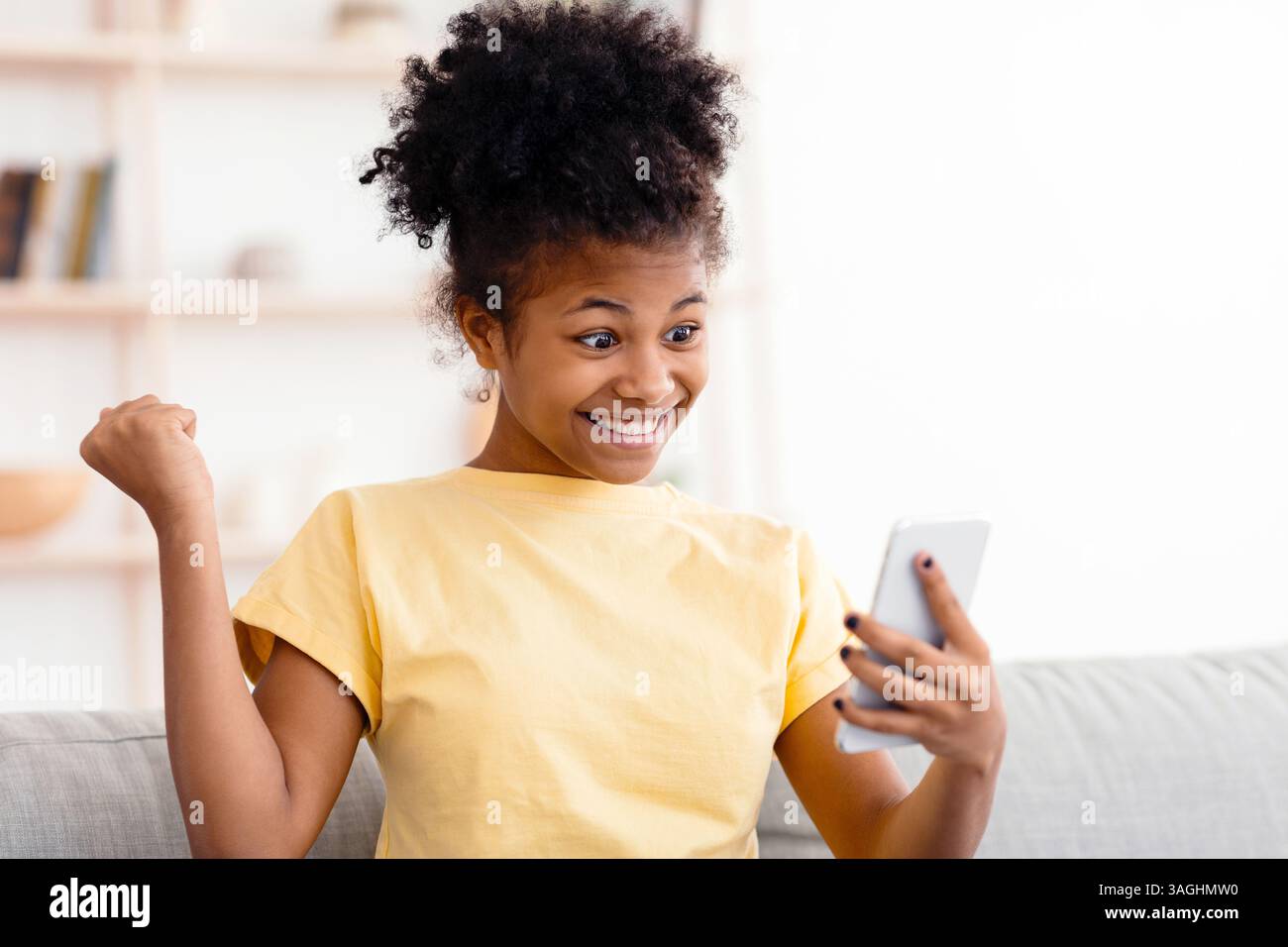 Black Girl Winning Game On Smartphone Sitting On Sofa Indoors Stock ...