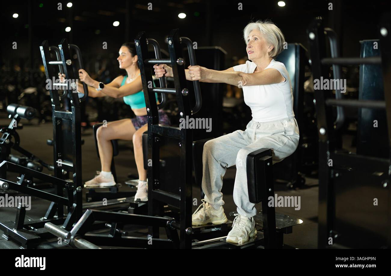 Senior woman uses leg abduction machine to strengthen muscles Stock ...