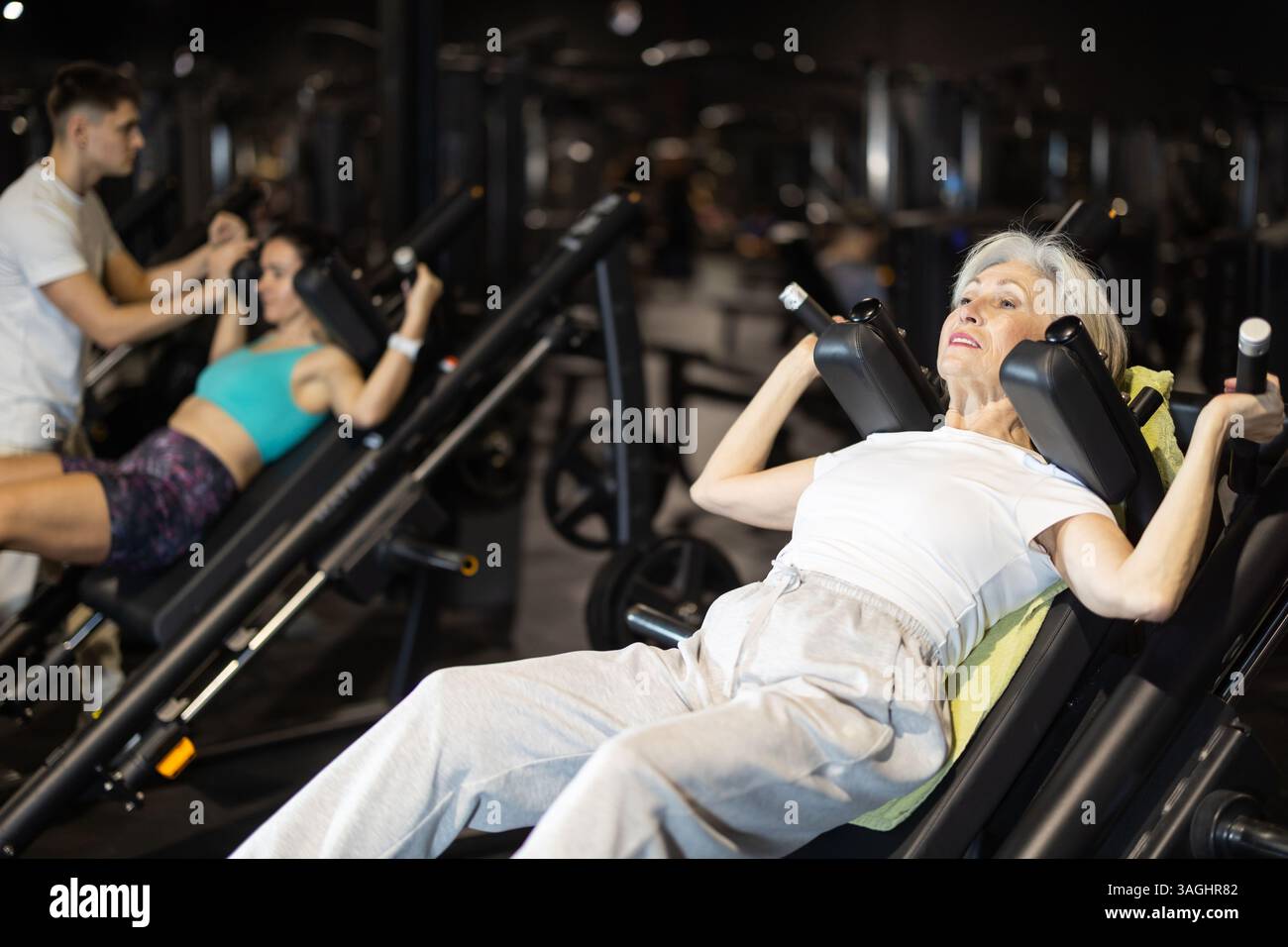 Senior woman uses hack squat machine to strengthen muscles Stock Photo ...