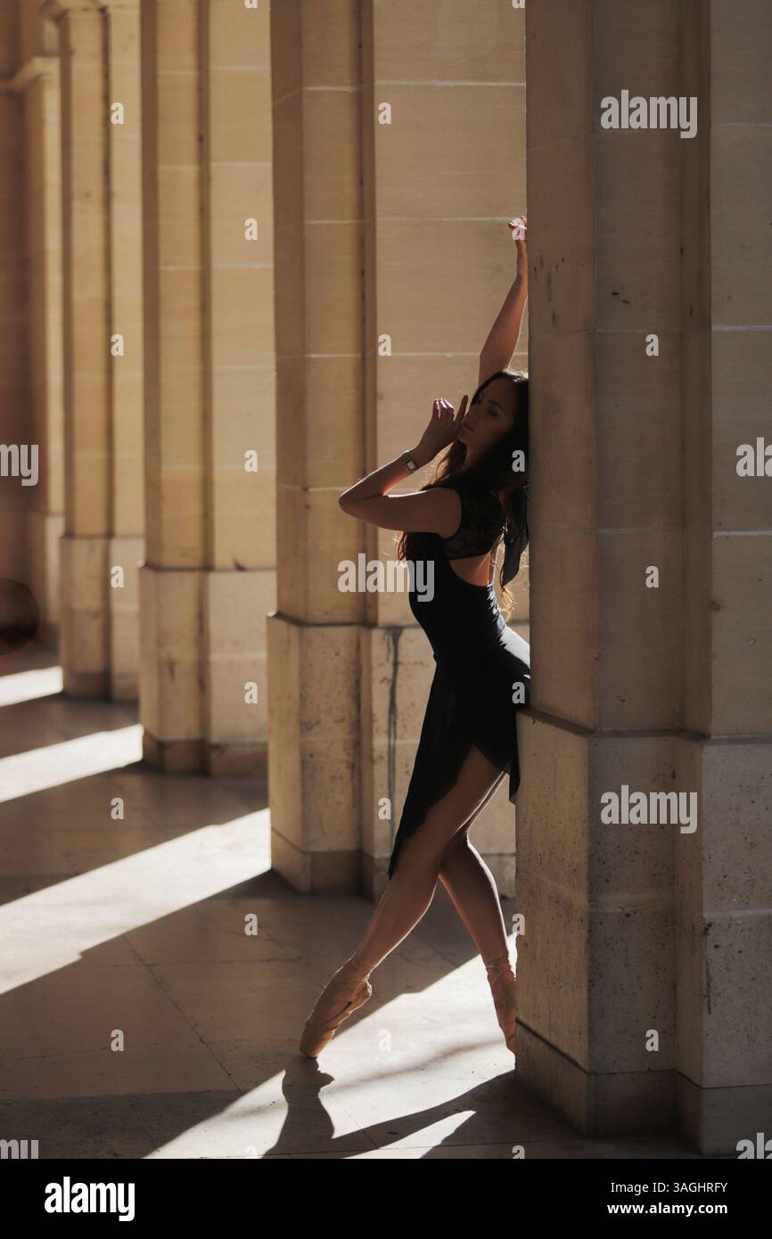 Ballet dancer striking elegant pose in stone arcade. Soft directional ...