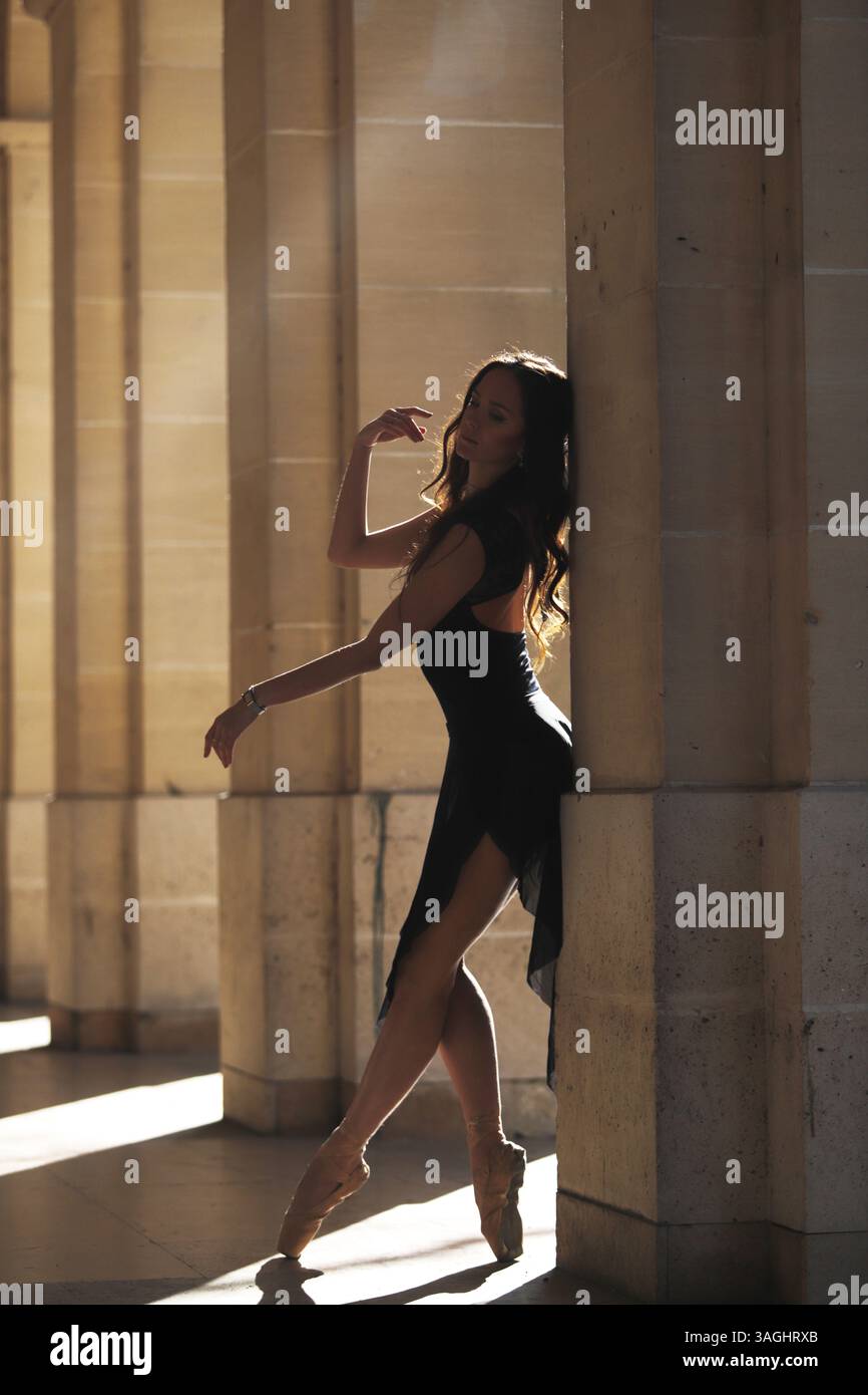 Ballet dancer en pointe posing in golden light beside elegant stone ...