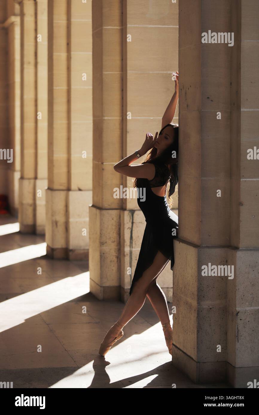 Ballet dancer en pointe striking elegant pose in golden sunlit corridor ...