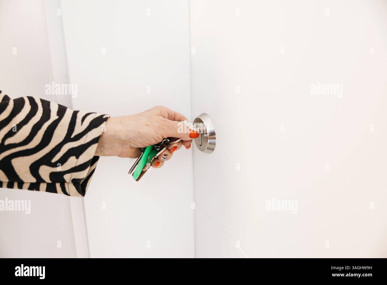 Woman inserting key into the lock of new apartment door Stock Photo - Alamy