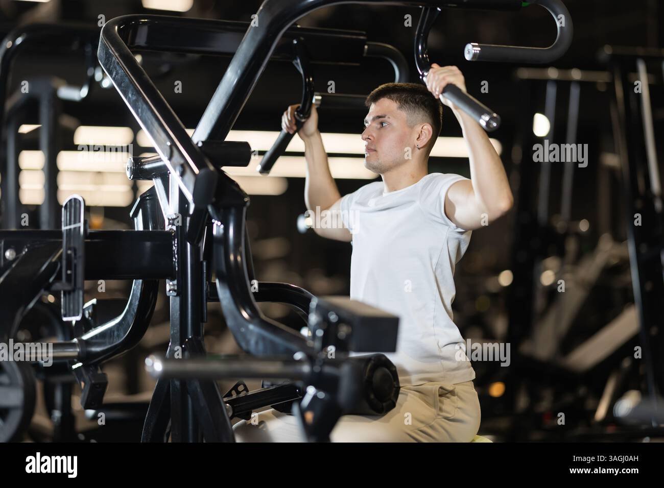 Young man training on plate-loaded lat pulldown machine at gym Stock ...