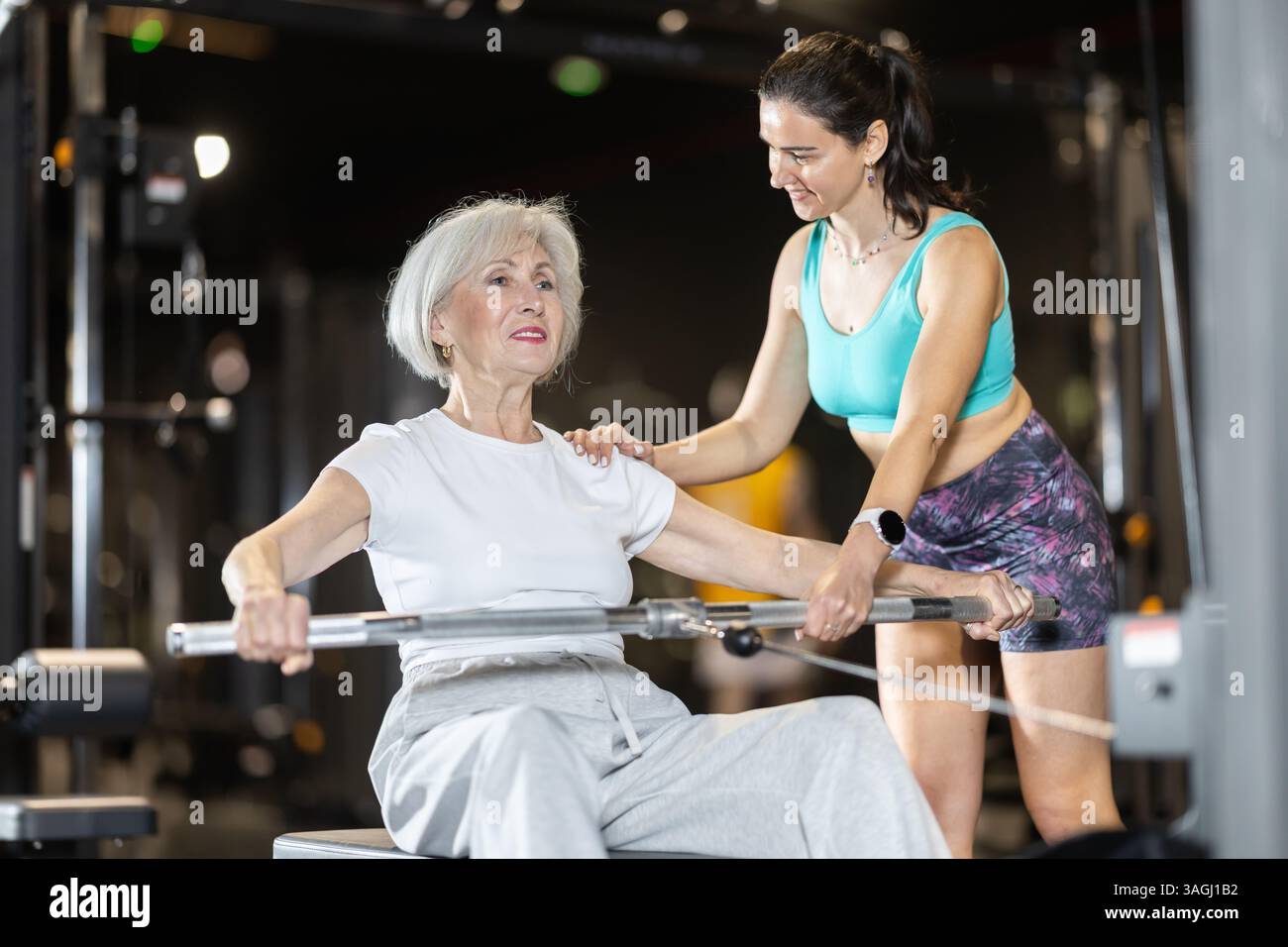 Older woman performing back workout with trainer Stock Photo - Alamy