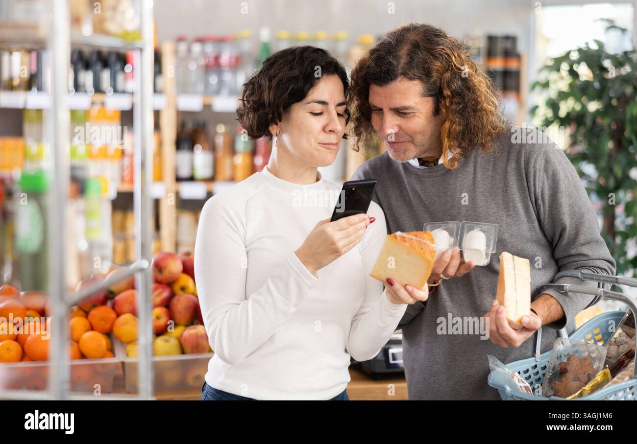 Husband and wife scans QR code on cheese label in grocery store Stock ...