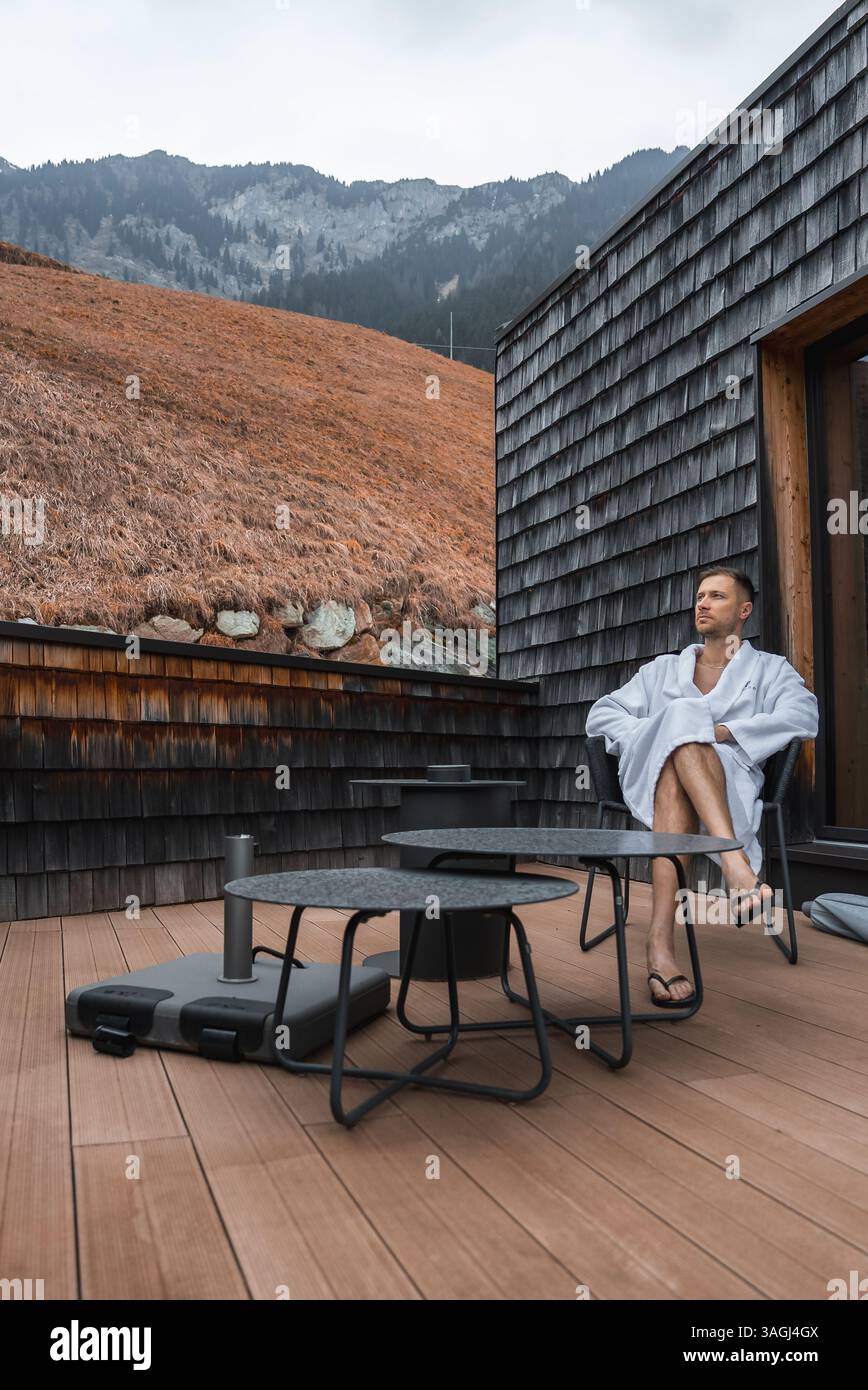 Man in White Robe Relaxing on Deck with Italian Alps Backdrop Stock ...
