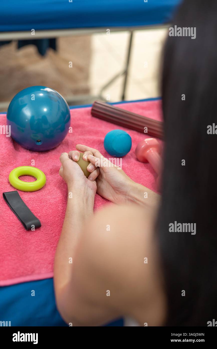 Woman practices hand strengthening exercises using wooden rollers ...