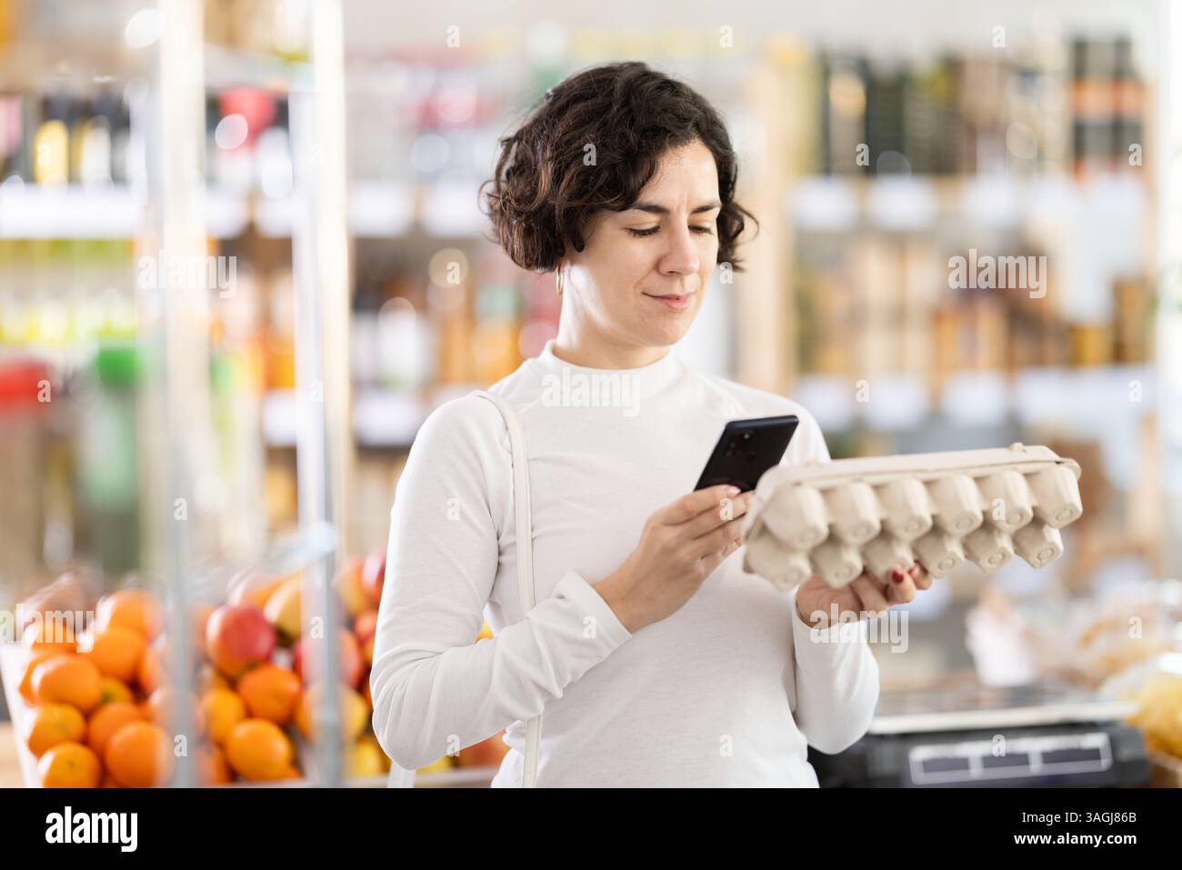 Adult woman scanning qr code of eggs Stock Photo - Alamy