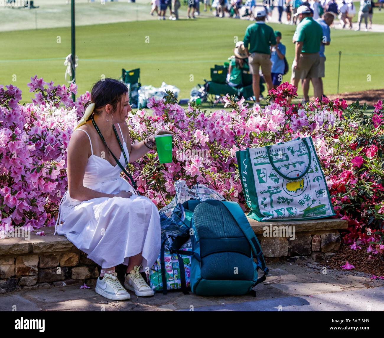 Augusta, United States. 08th Apr, 2025. A patron sits beside blooming ...
