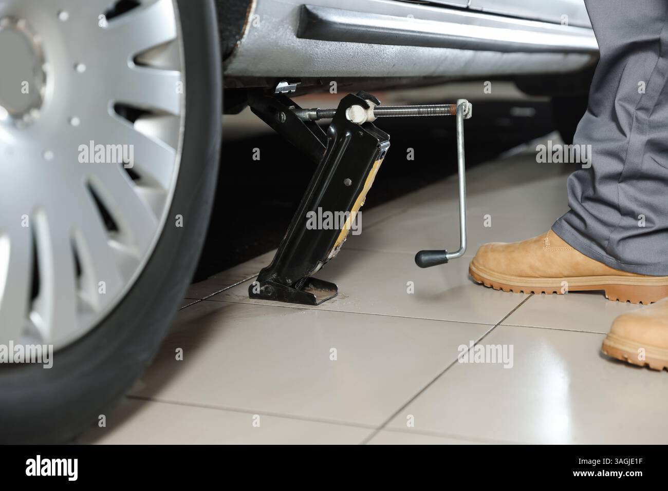 Car lifted by scissor jack. Auto mechanic repairing vehicle at service ...